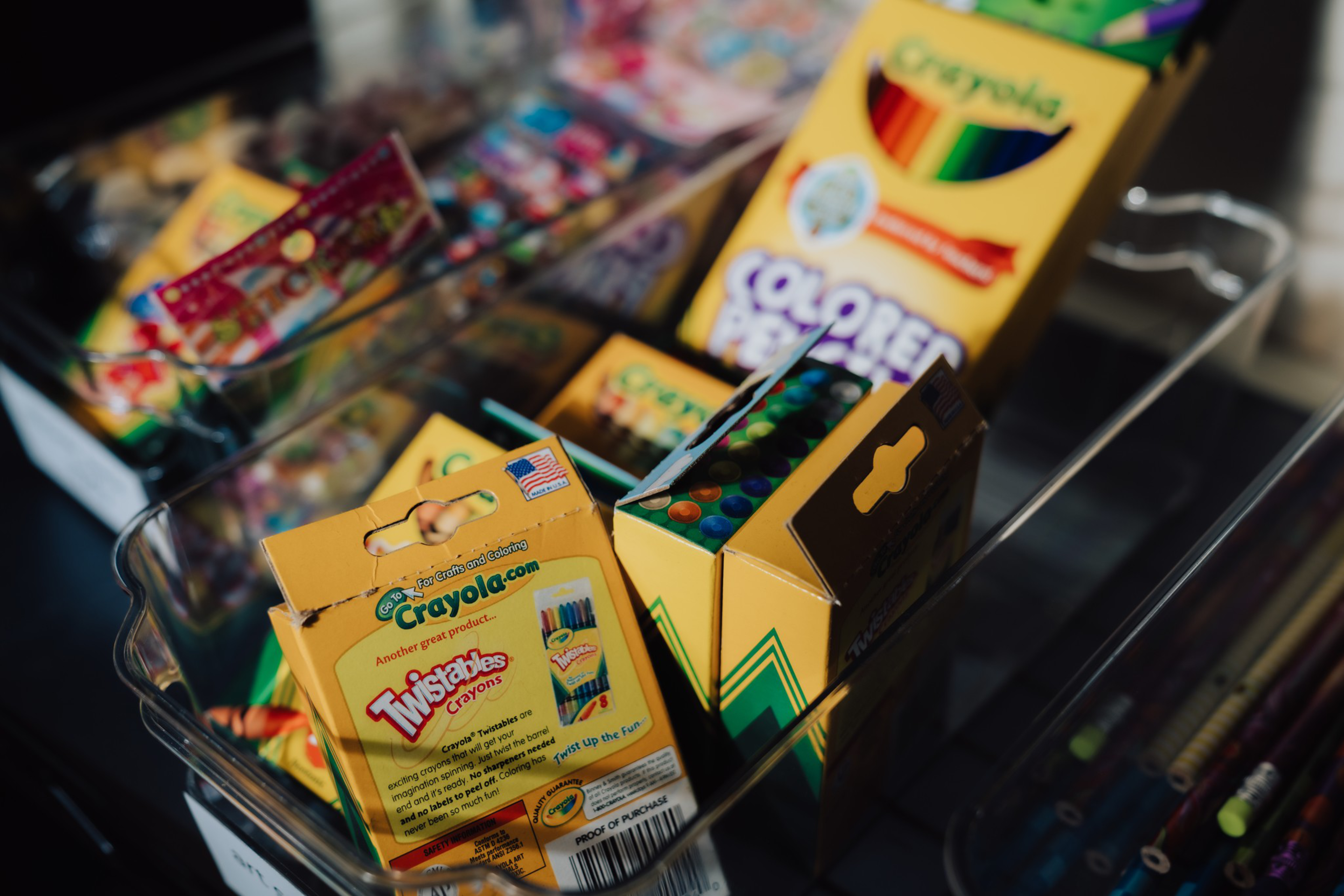 Boxes of Crayola crayons and colored pencils are organized in clear ...
