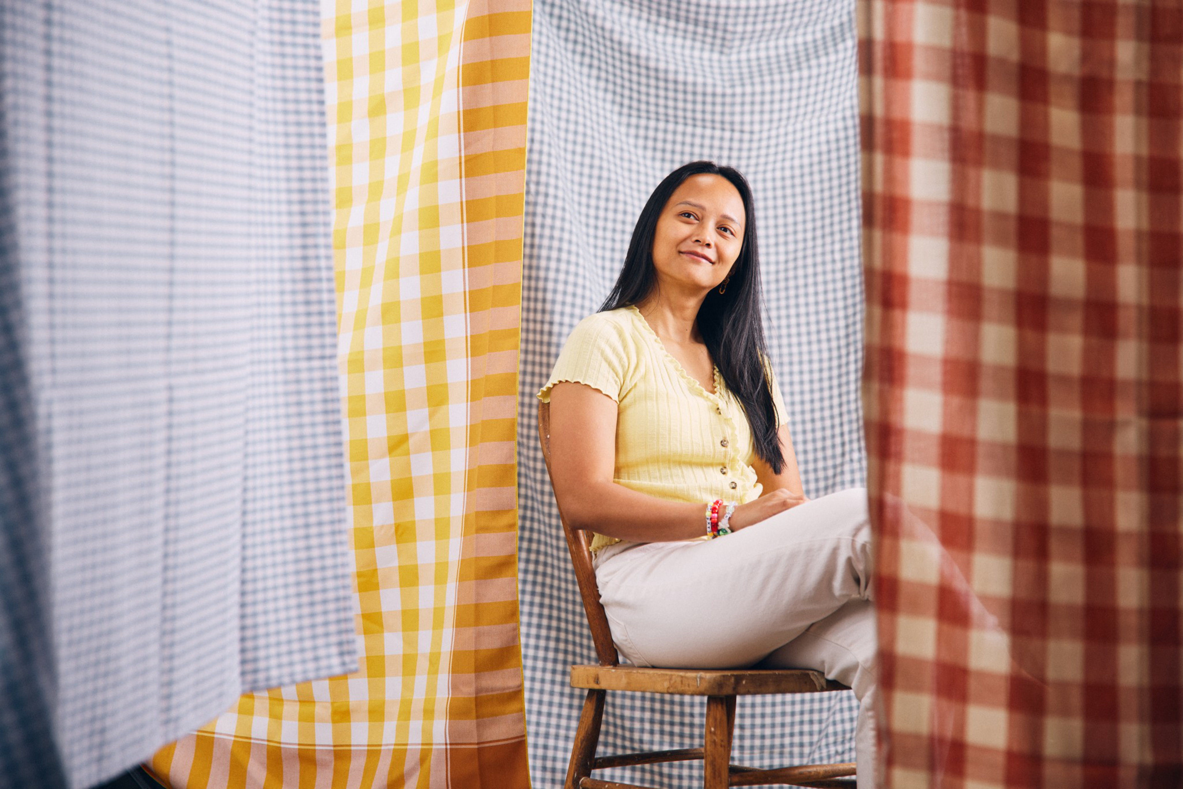 A woman with long black hair wearing a yellow shirt and white pants ...