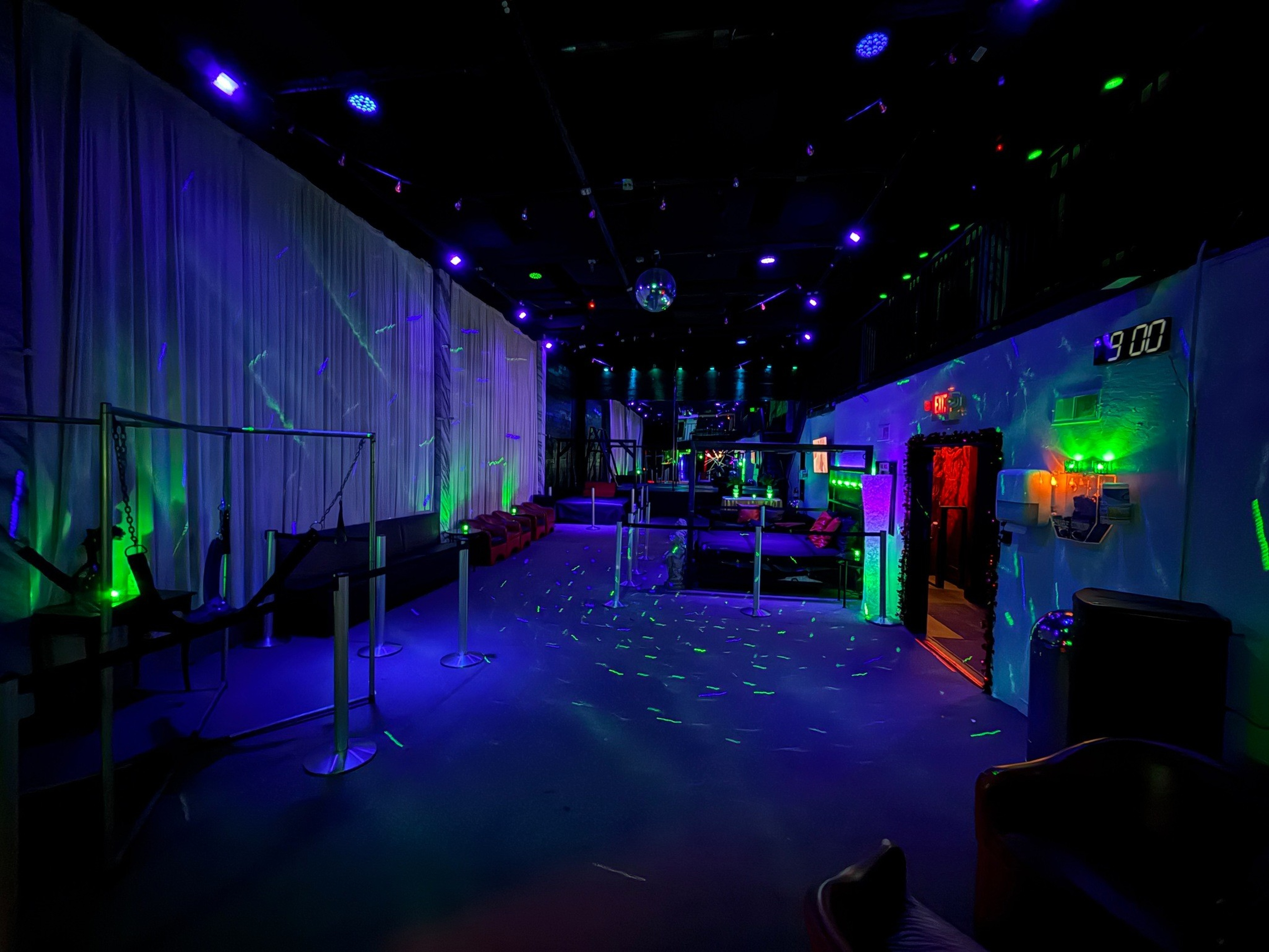 A dimly lit room with colorful neon lights, a disco ball, lounge ...