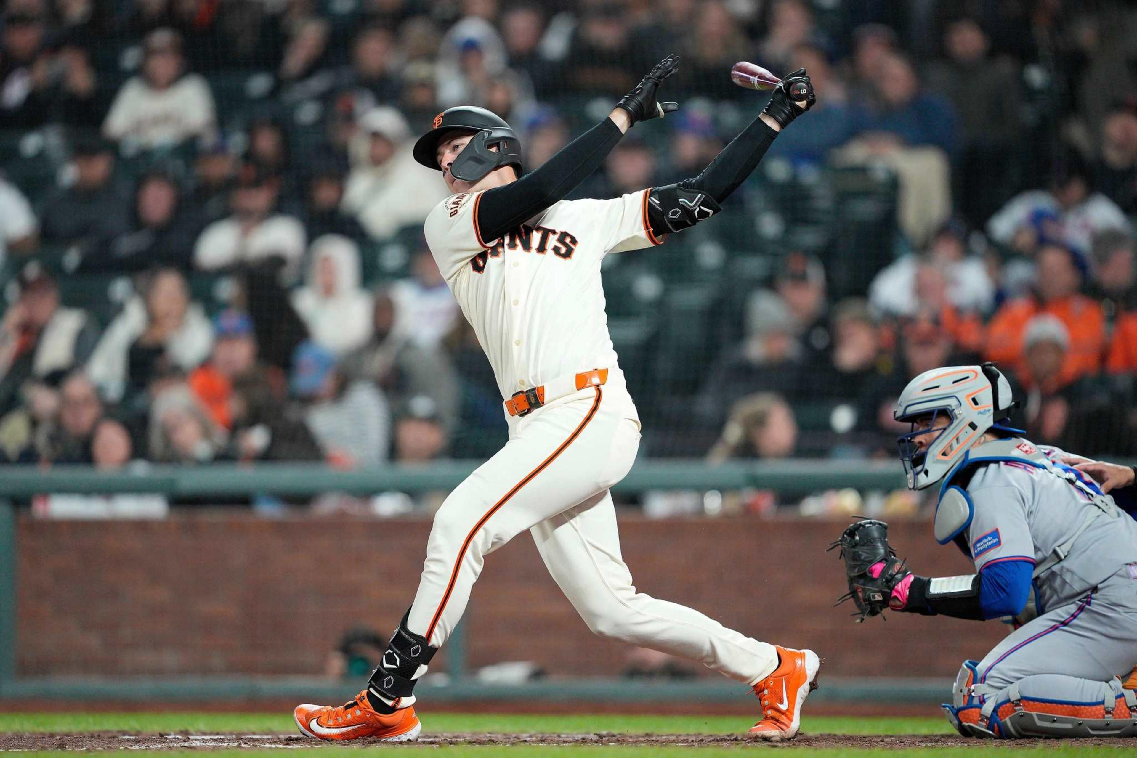 A baseball batter wearing a Giants uniform swings at a pitch while the ...