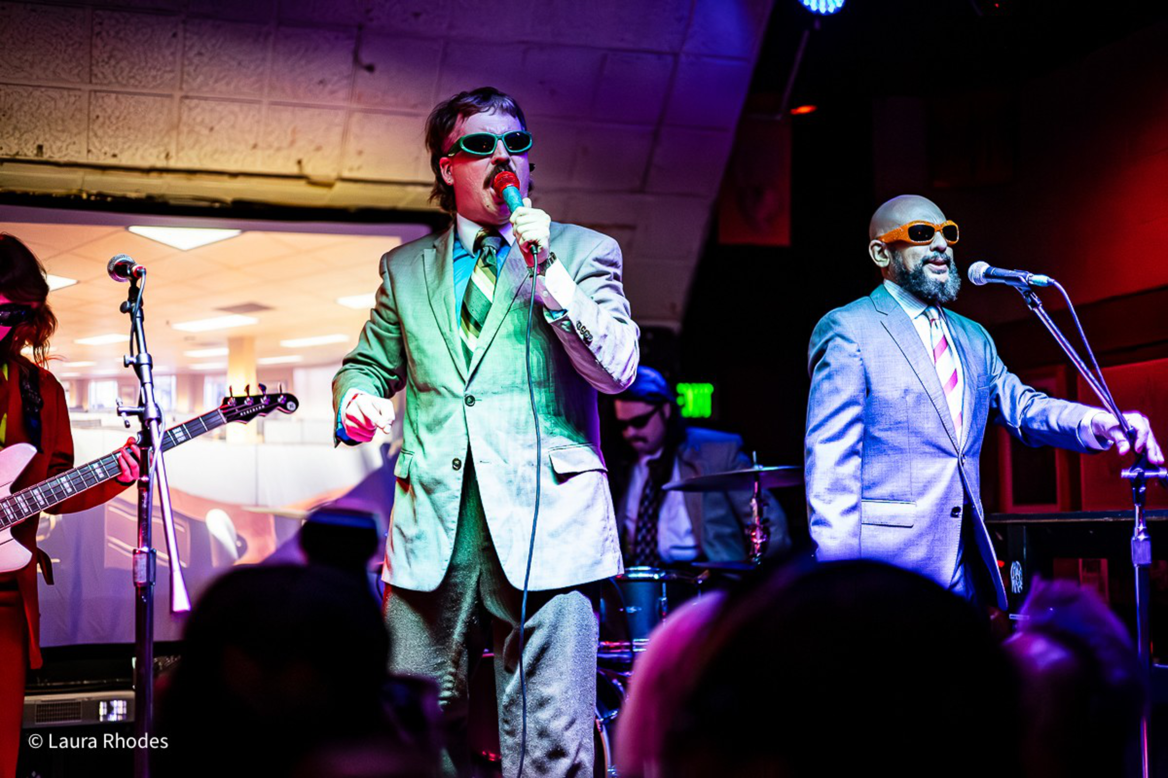 Two men in suits and sunglasses sing on stage with microphones ...