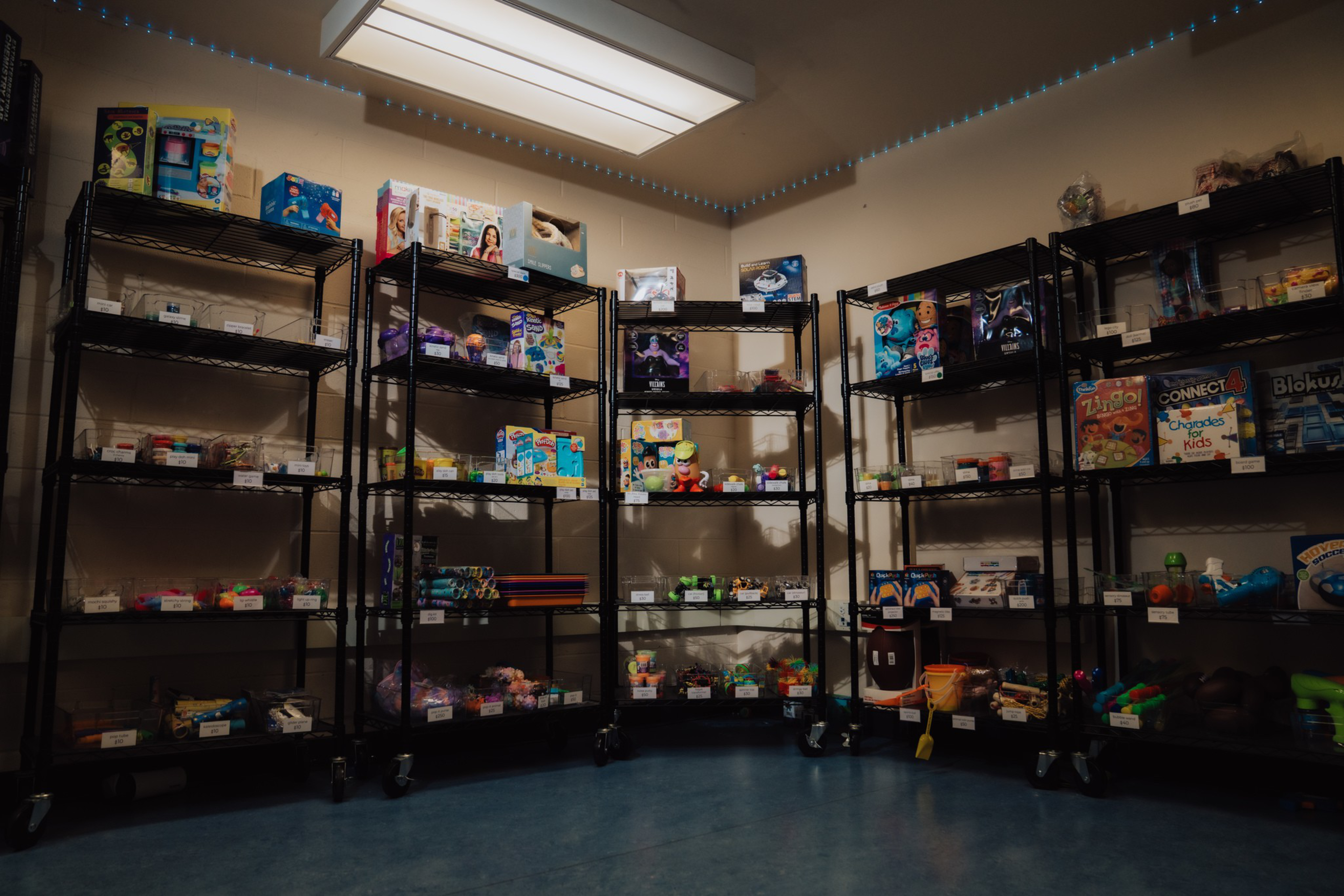Black metal shelves on wheels hold various boxed board games, toys, and ...