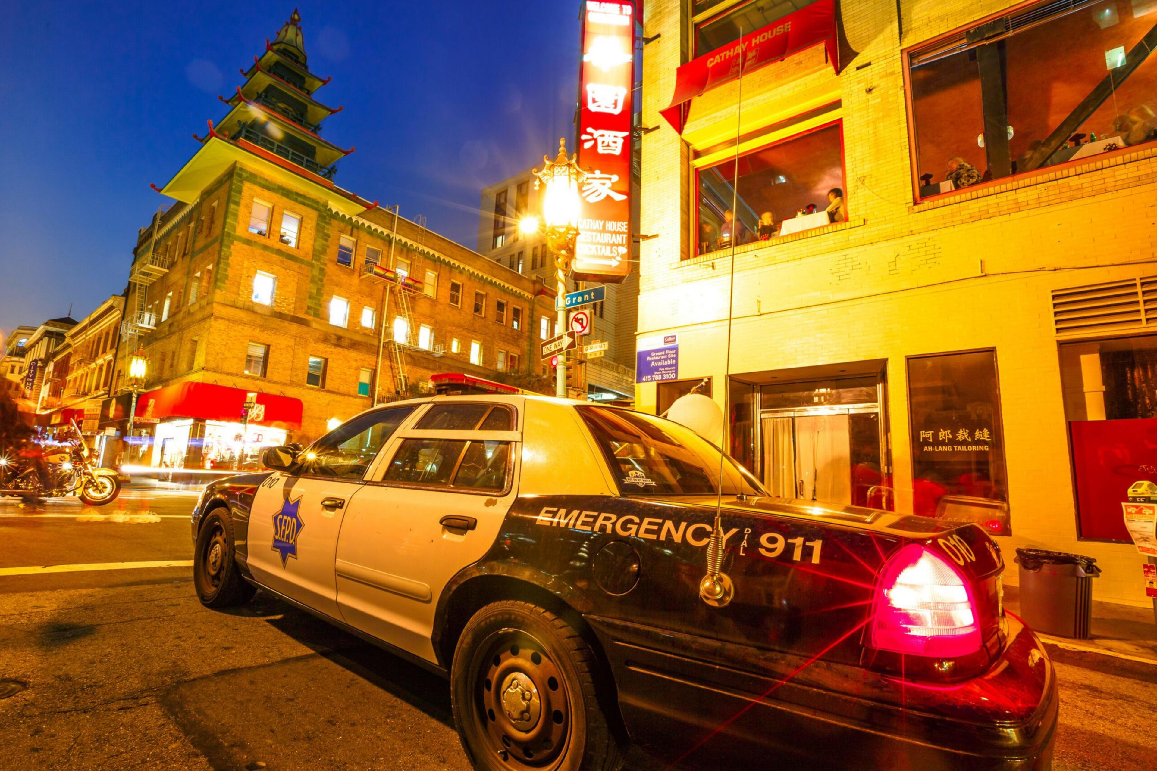A black and white police car with flashing lights is parked on a street ...