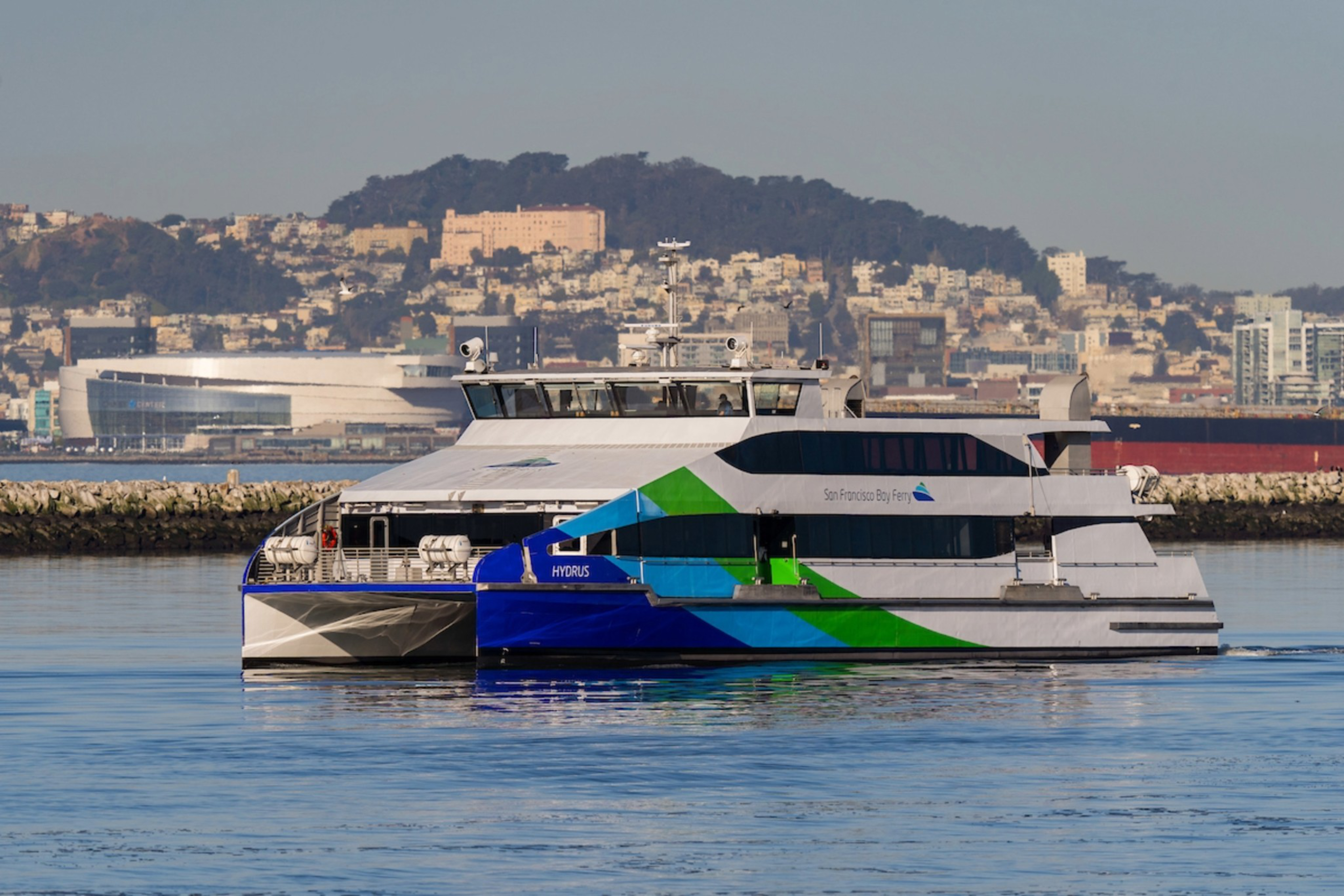 A modern blue, green, and white ferry named Hydrus floats on calm water ...