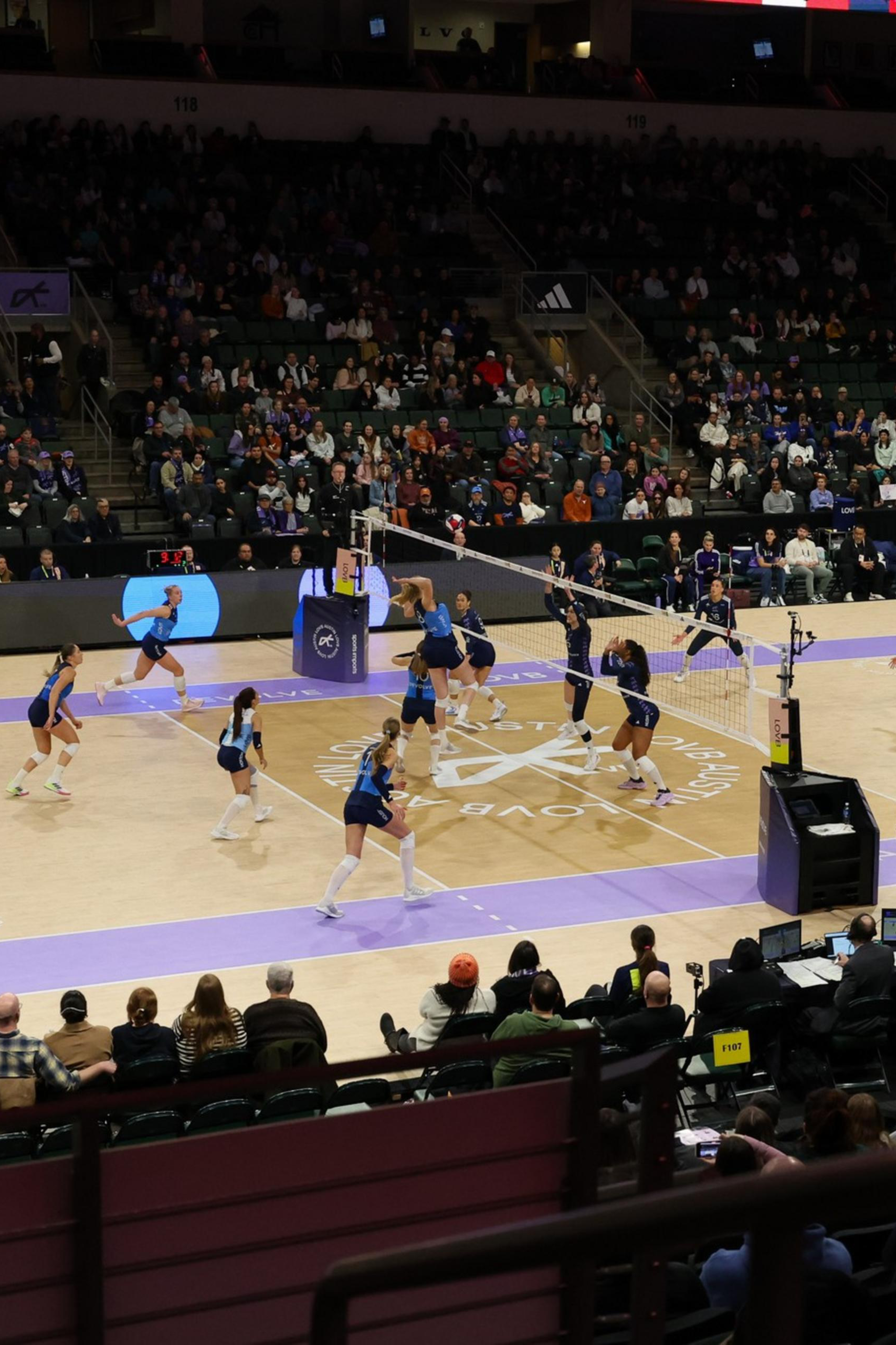 A volleyball match is in progress on a court with a purple border ...