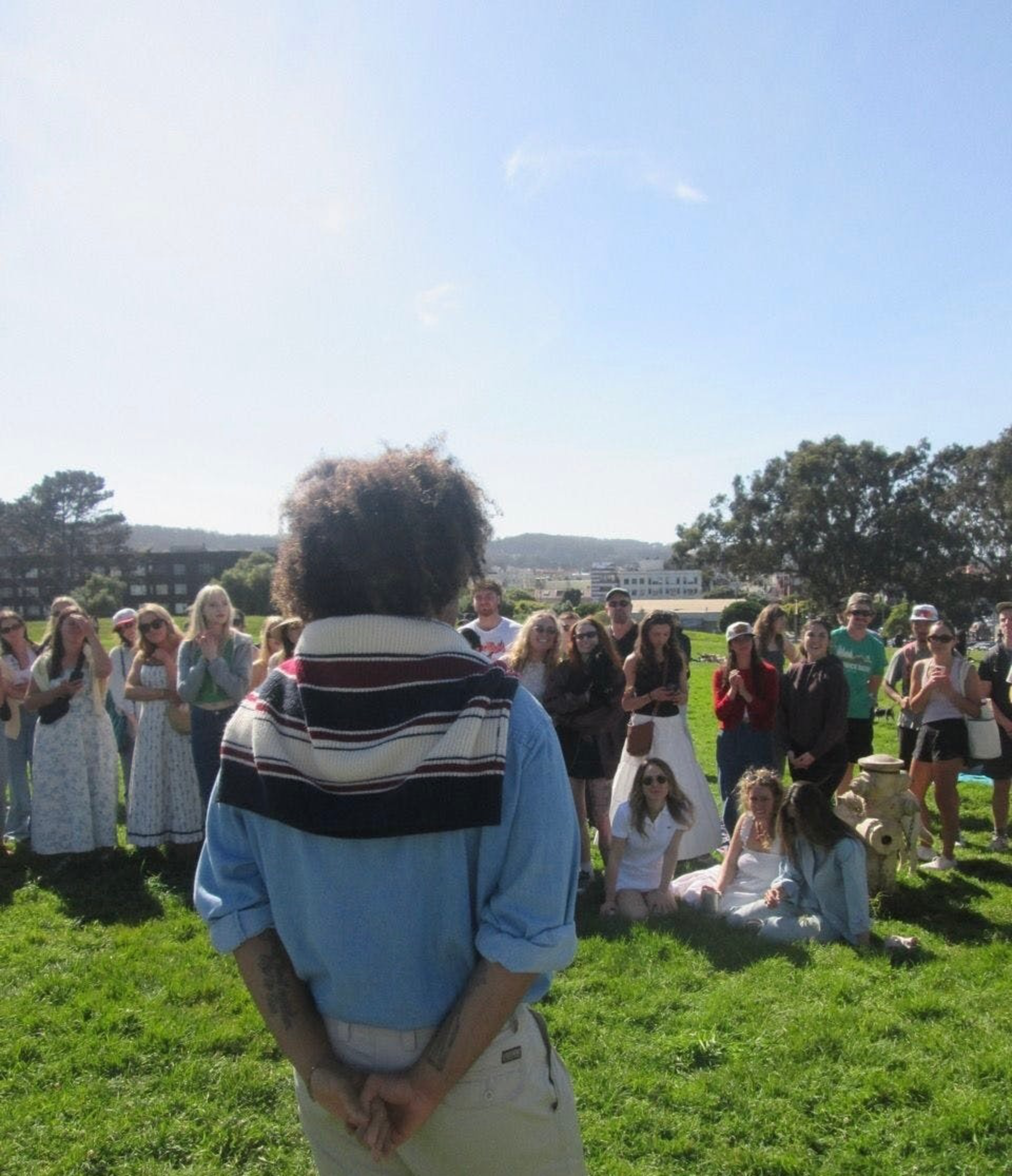 A person with curly hair stands with their back to the camera, facing a ...